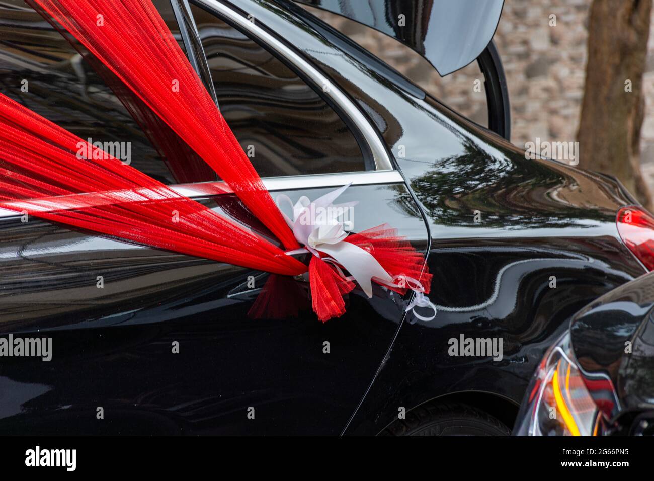 Black wedding car, red organza fabric, ribbon bow Stock Photo - Alamy