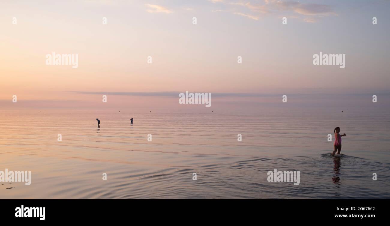 Golden hour at seaside resort people wading waters in Kauguri Jurmala ...