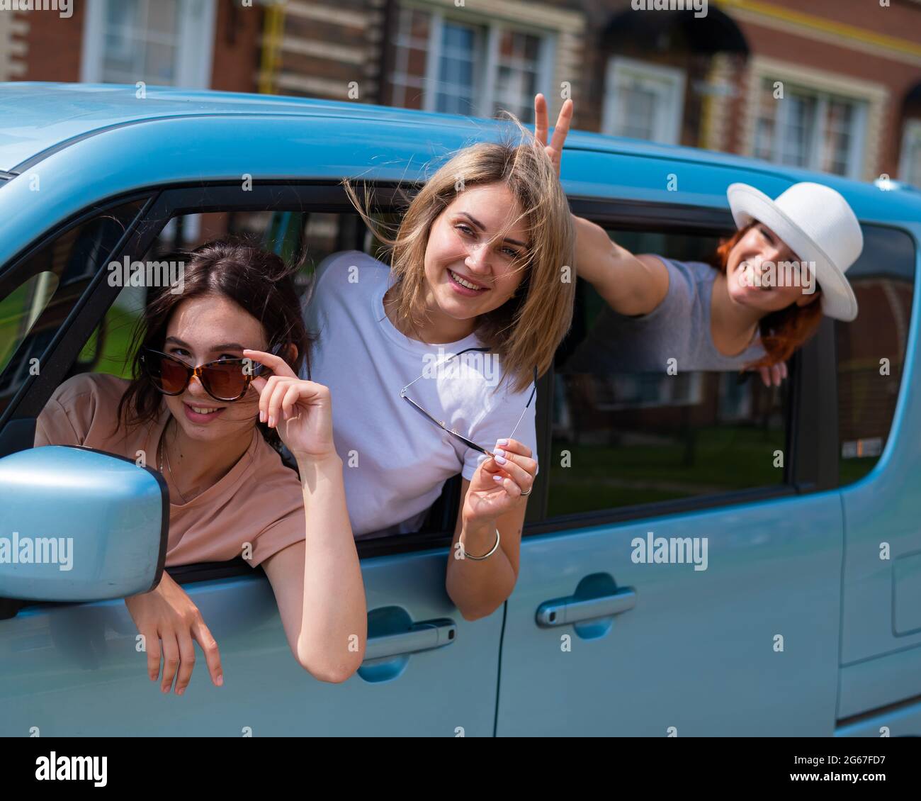 Three friends look out of the car window while traveling Stock Photo ...