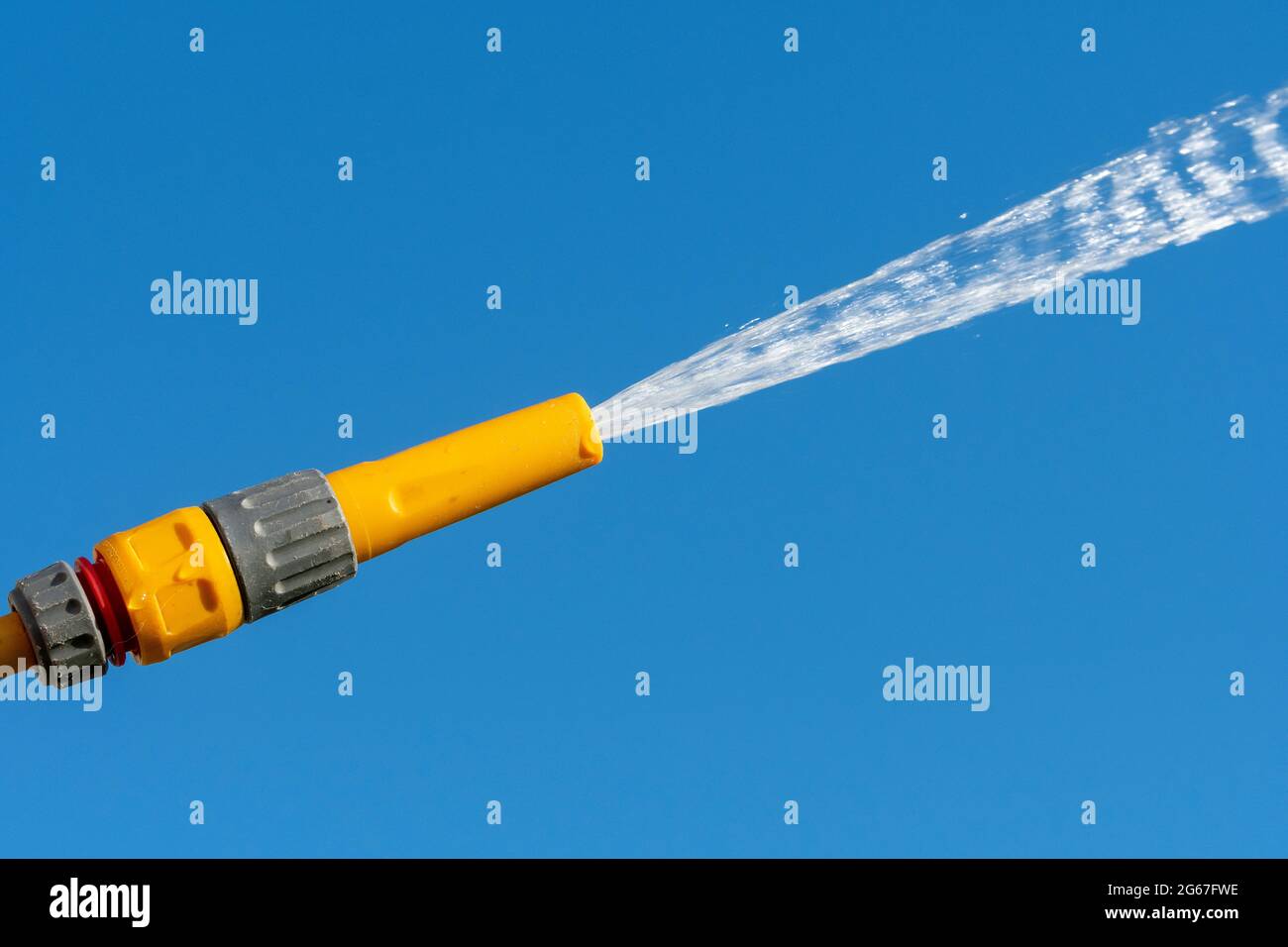 Water spraying out of a hosepipe against a clear blue sky, UK Stock ...