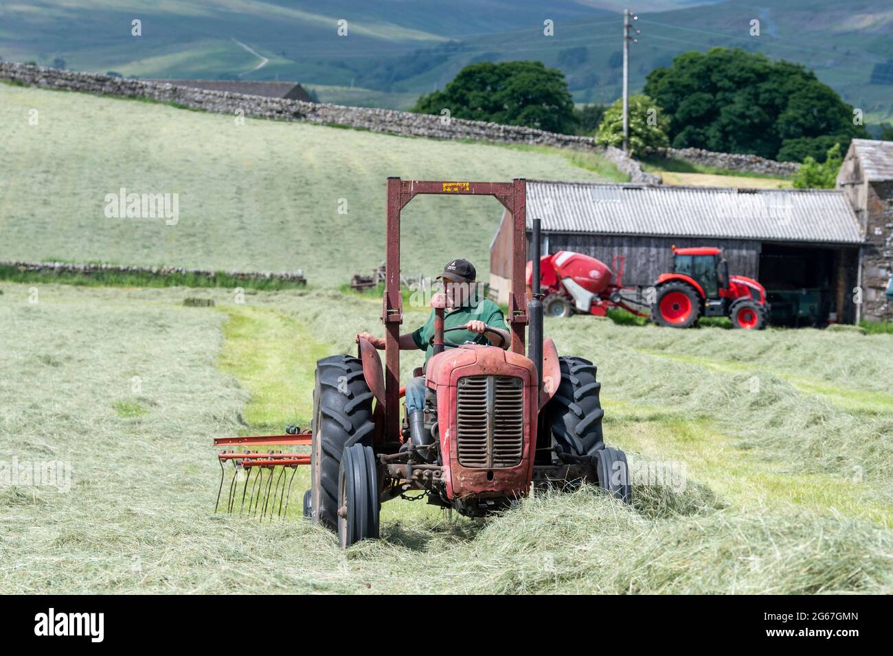 Farmer on a 1963 Massey Ferguson 35, rowing up hay ready to be baled ...