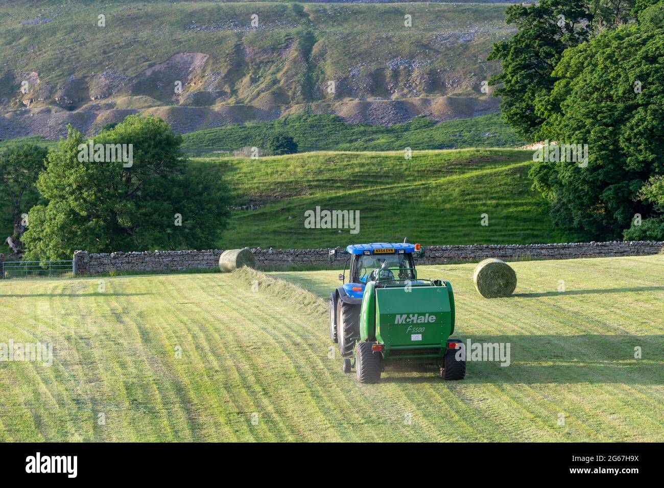 Farmer making big round bales of haylage with a New Holland TS135 ...