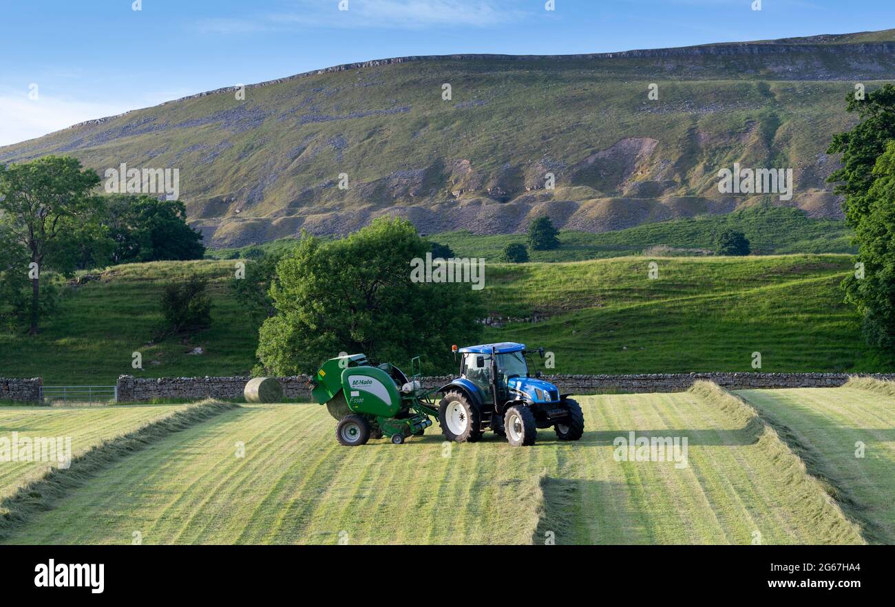 Farmer making big round bales of haylage with a New Holland TS135 ...