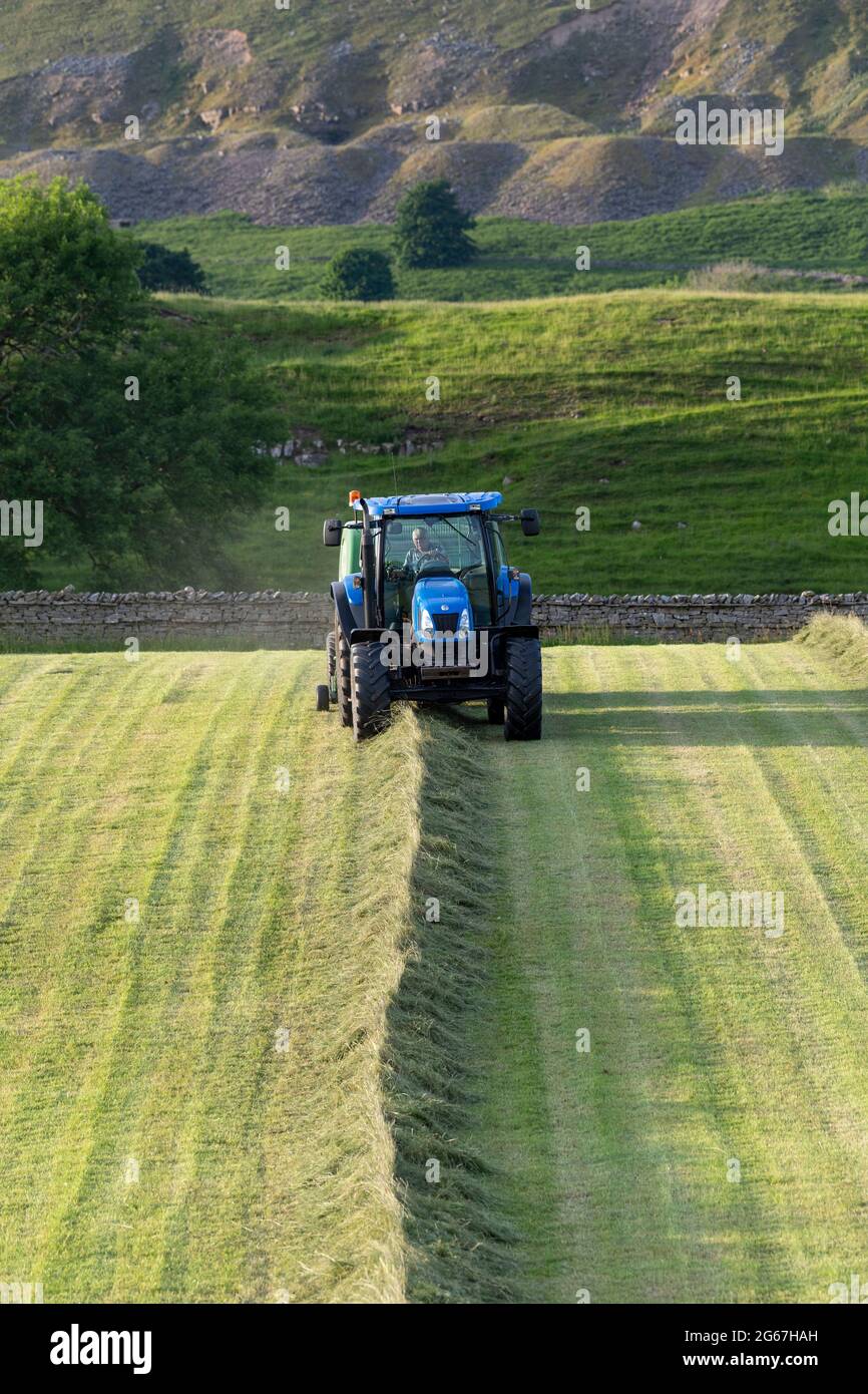 Farmer making big round bales of haylage with a New Holland TS135 ...