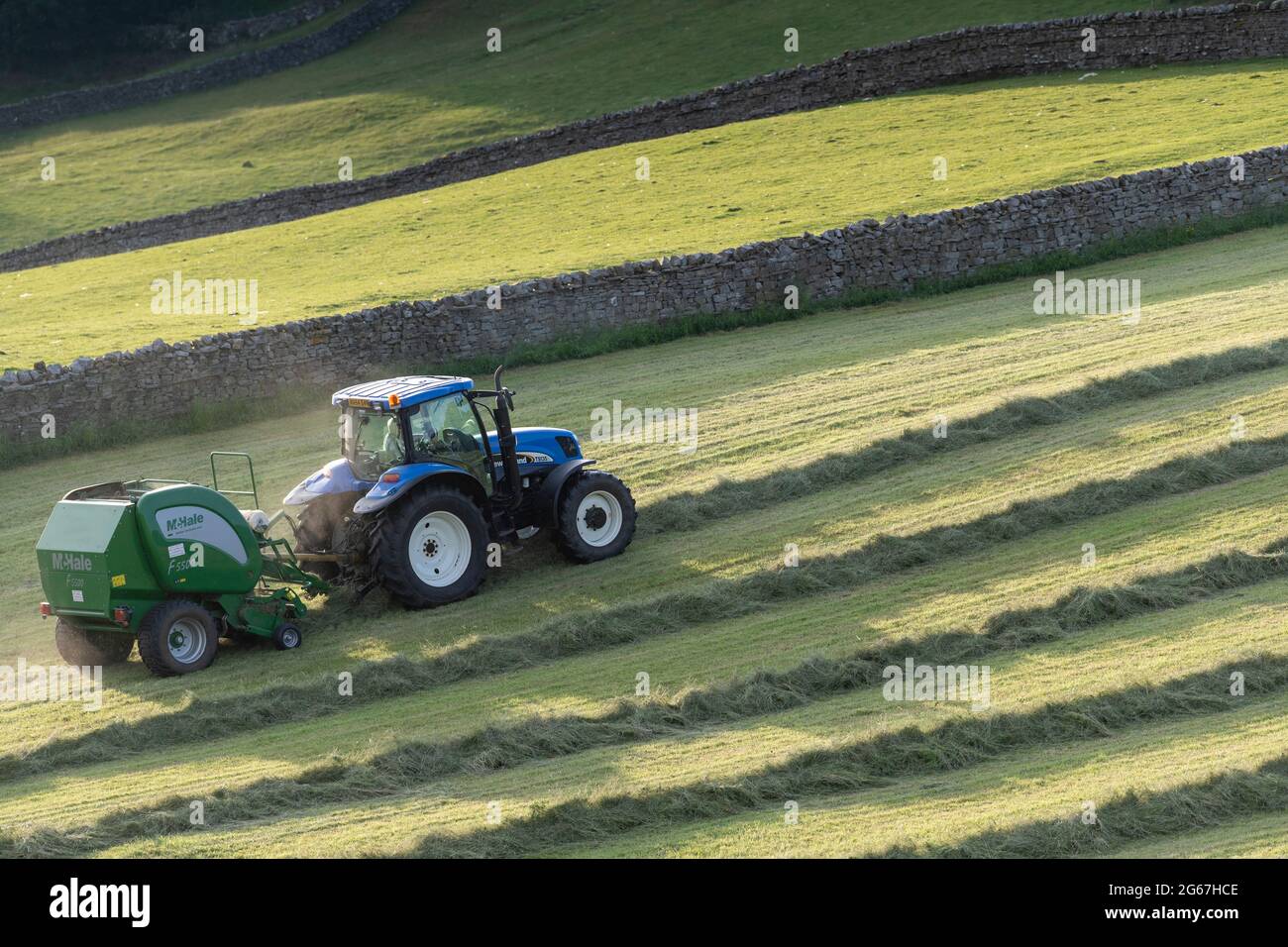 Farmer making big round bales of haylage with a New Holland TS135 ...