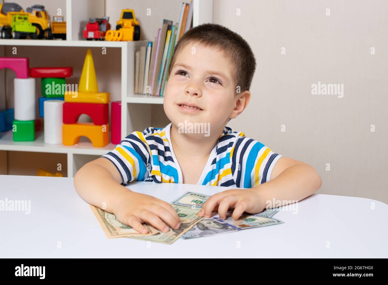 A beautiful child and dollar bills. The boy is thinking about where to ...