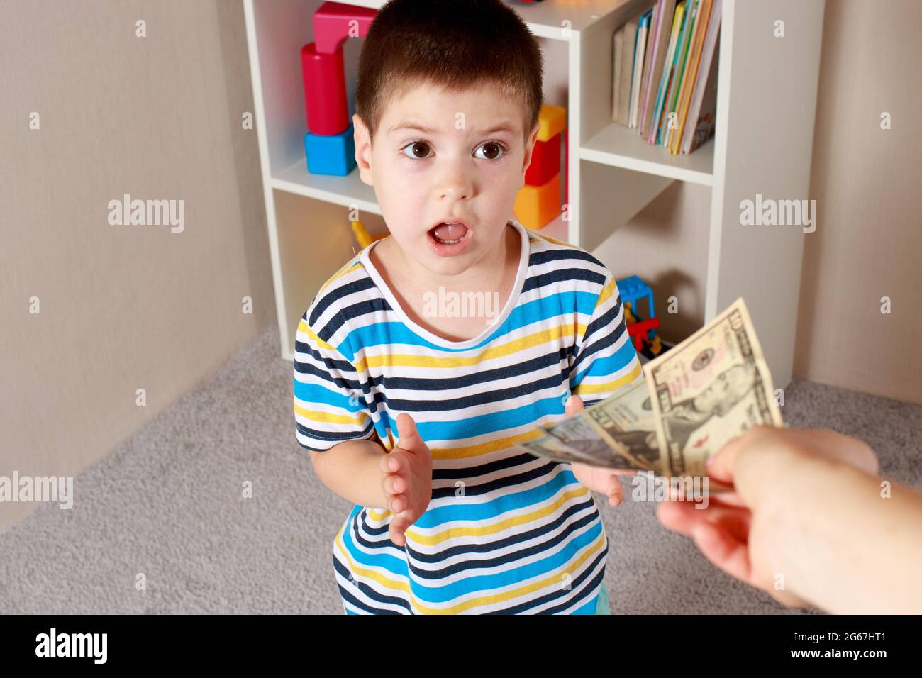 A small child boy takes dollar bills from the hands of an adult parent ...