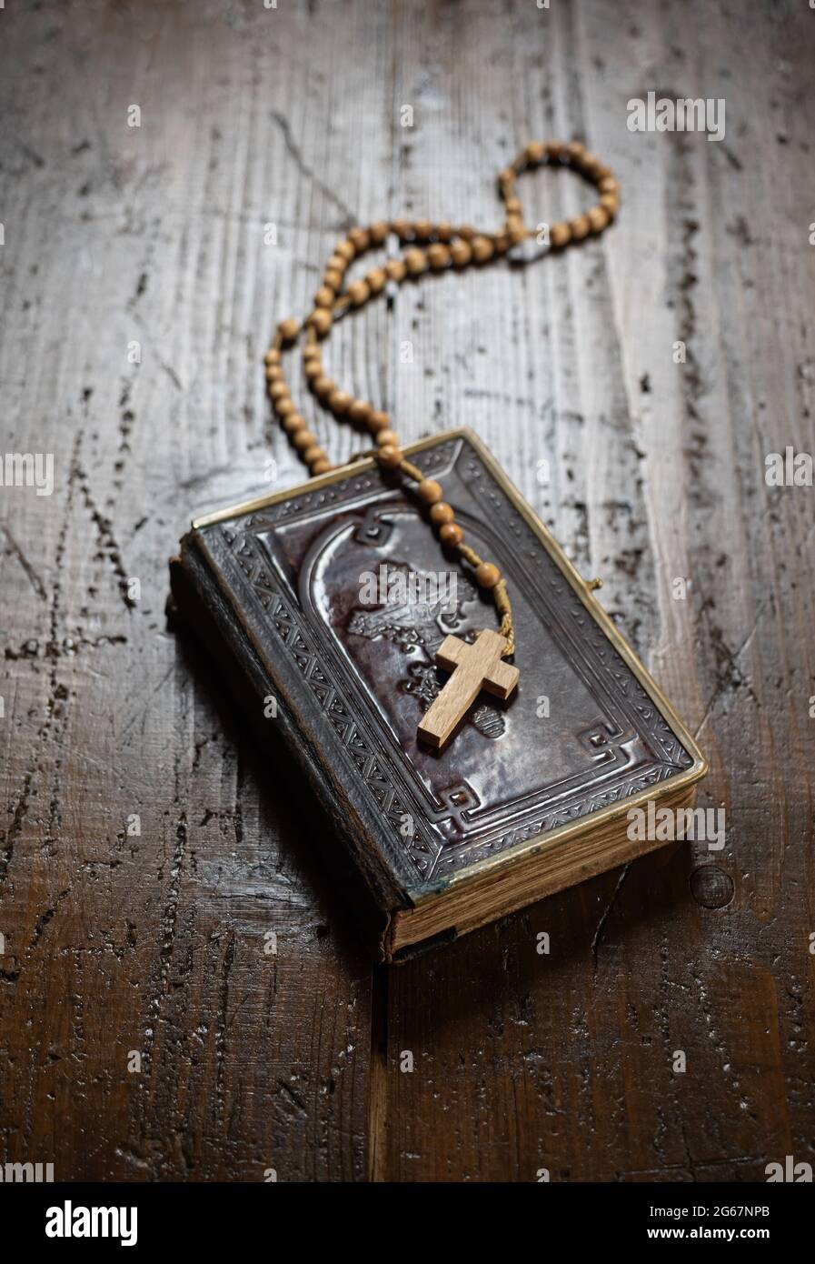 Rosary with cross laying on old Holy Bible book on rustic wooden table ...