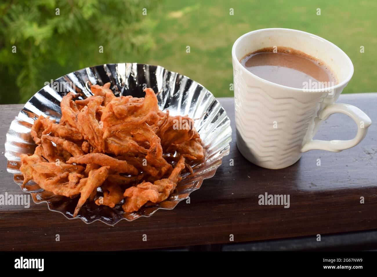 Hot crispy onion pakoda plate with hot masala tea served in outdoors ...