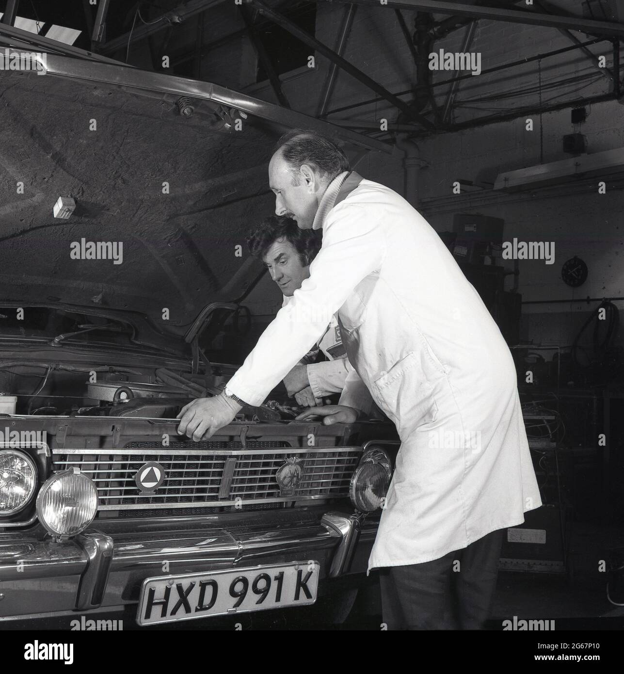 1970s, historical, inside a car repair workshop, two garage mechanics ...