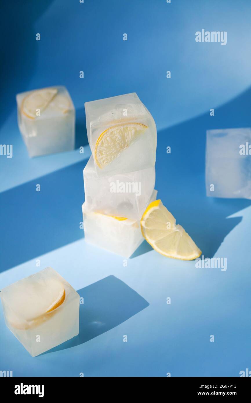 Modern composition of the frozen slices of lemon and ice cubes on a blue background Stock Photo ...
