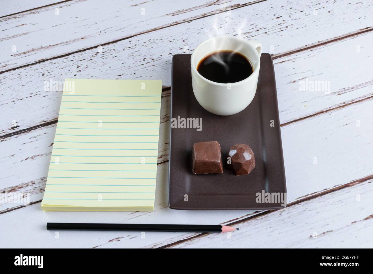 Notepad next to a cup of coffee and dark chocolate candies Stock Photo ...