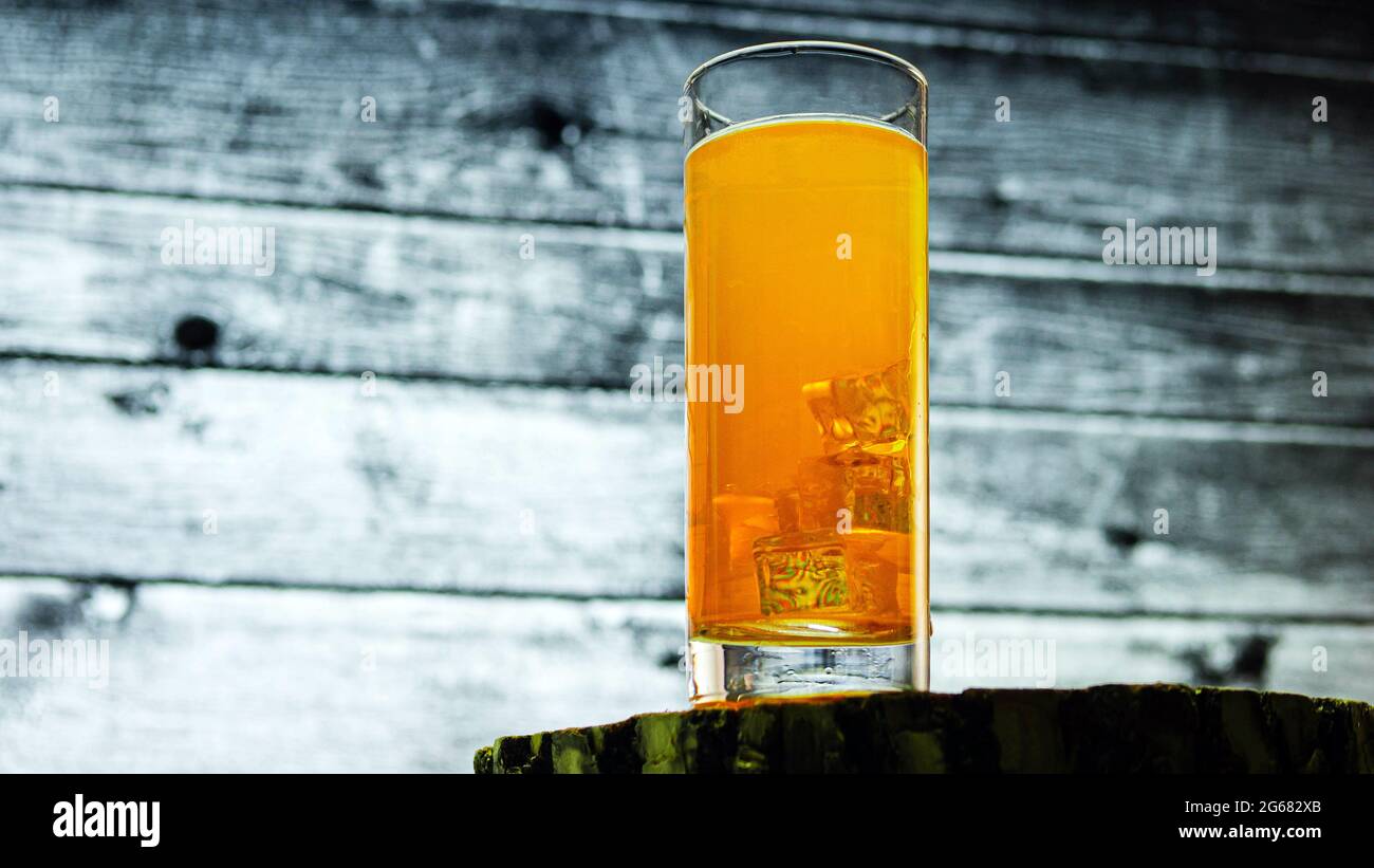 Yellow lemonade in a glass transparent on a background of wooden boards ...