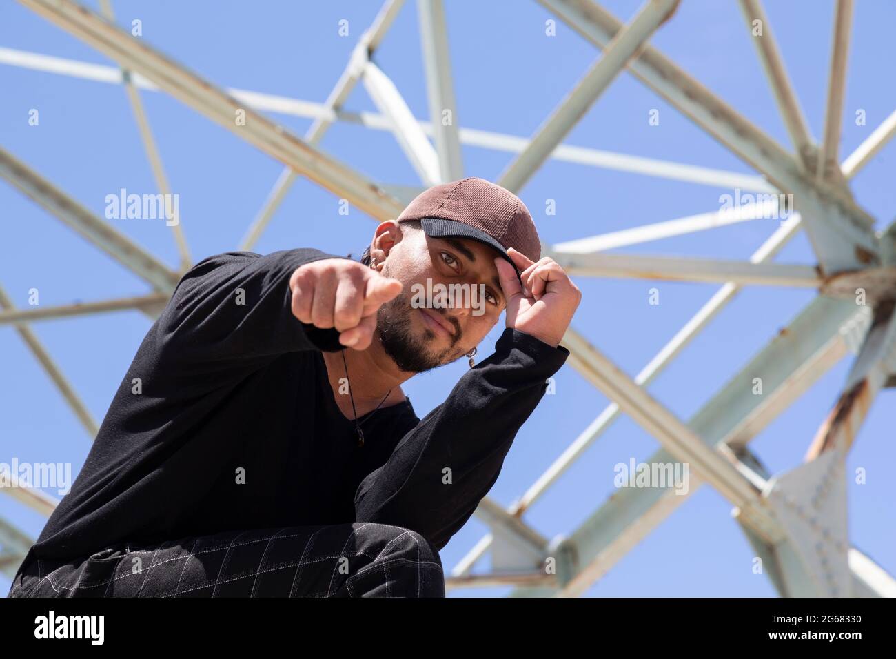 Young hispanic latin street dancer with blue sky background and metal ...
