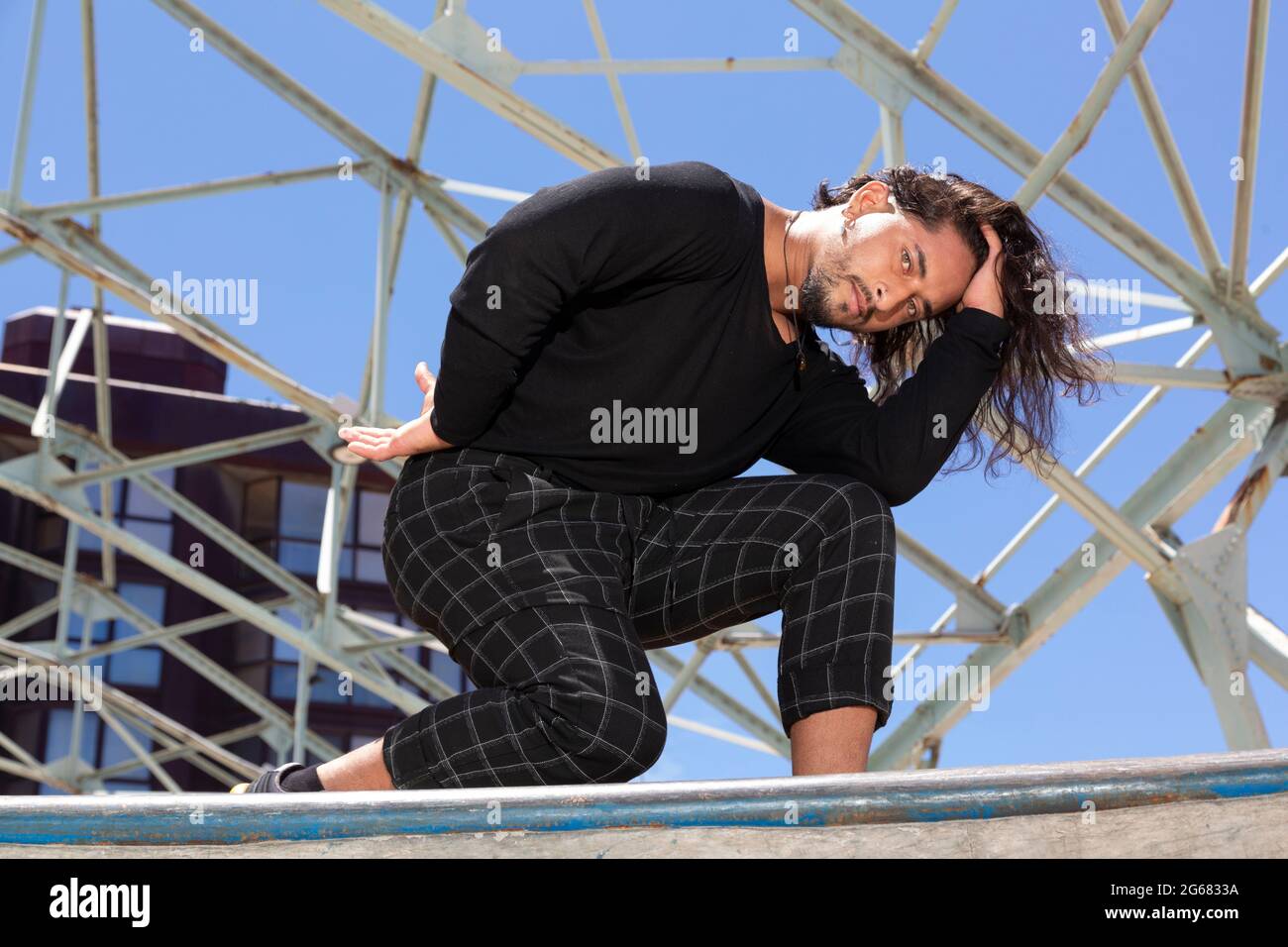 Young hispanic latin street dancer with blue sky background and metal ...