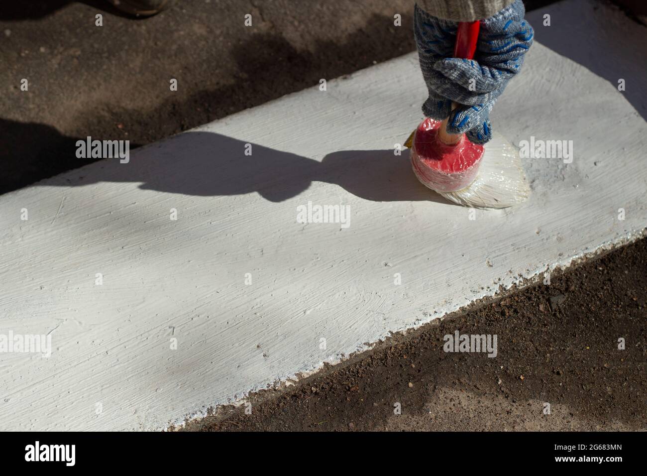 Paints the kerb with white paint. Brush with paint for the road curb ...
