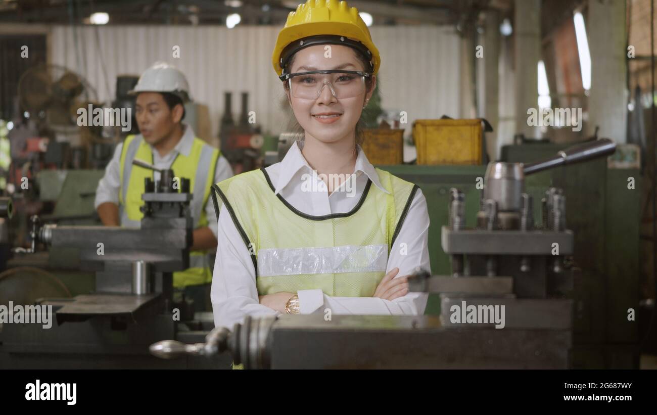 Portrait Asian engineer woman worker wear safety goggles control lathe ...