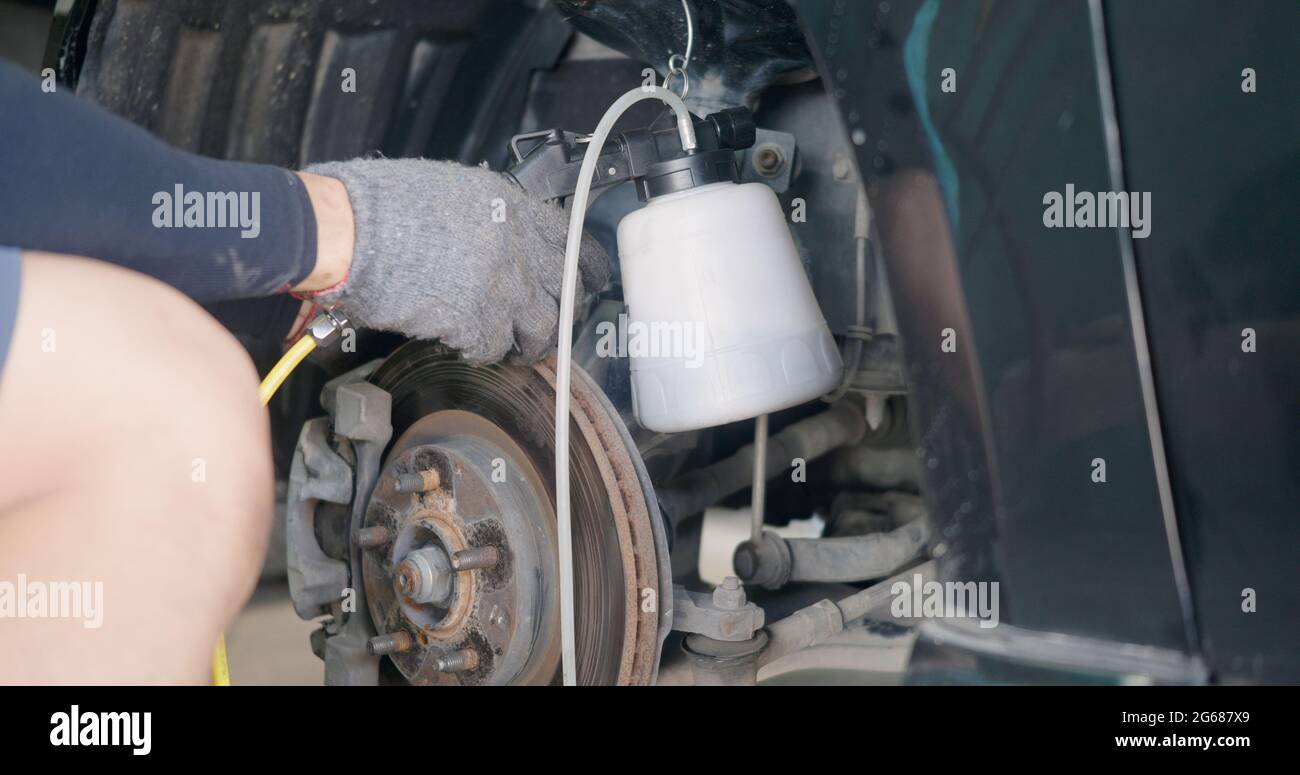 Auto mechanic replacing brake fluid on a vehicle, technician bleed air ...