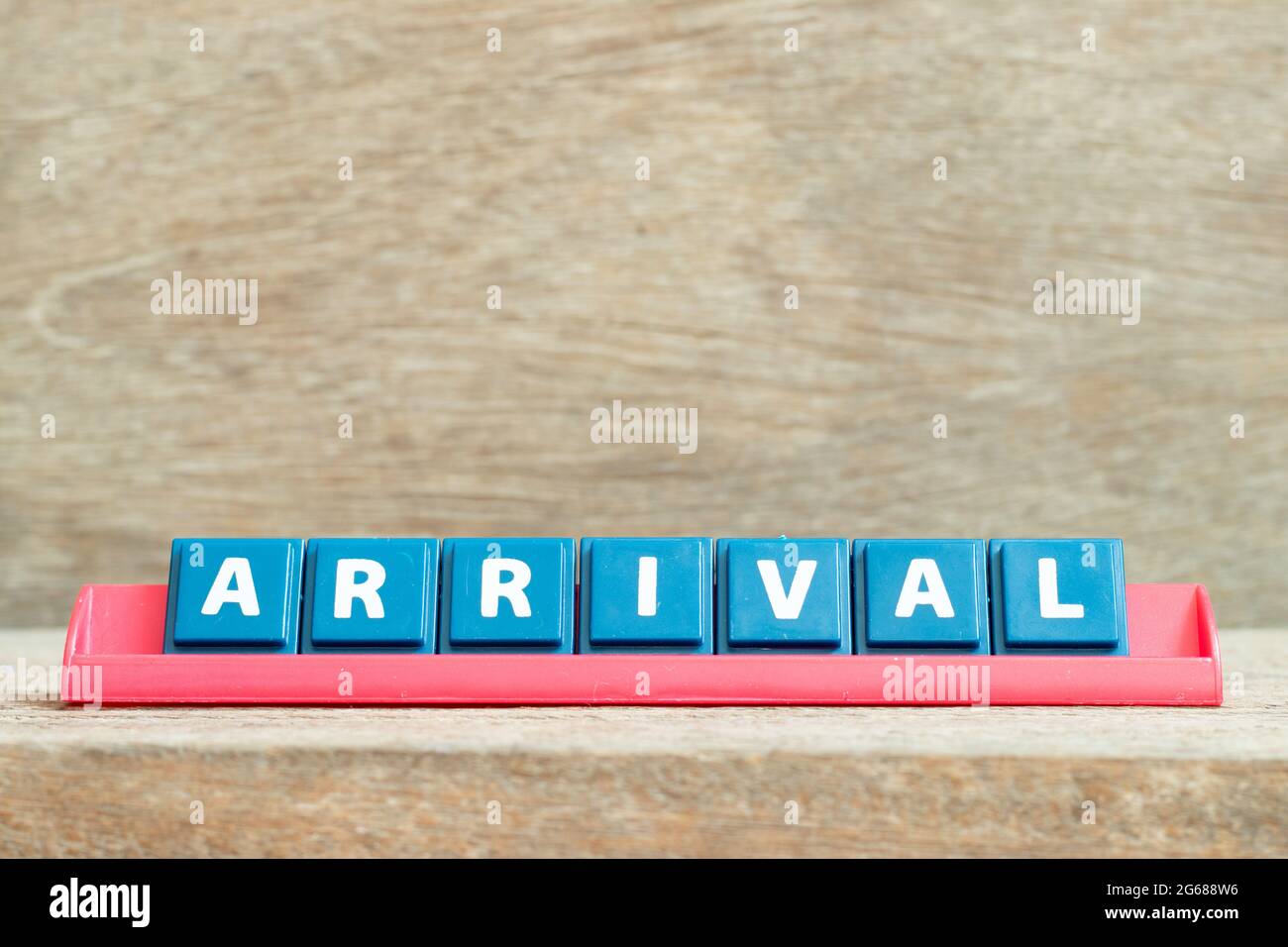 Tile alphabet letter with word arrival in red color rack on wood ...