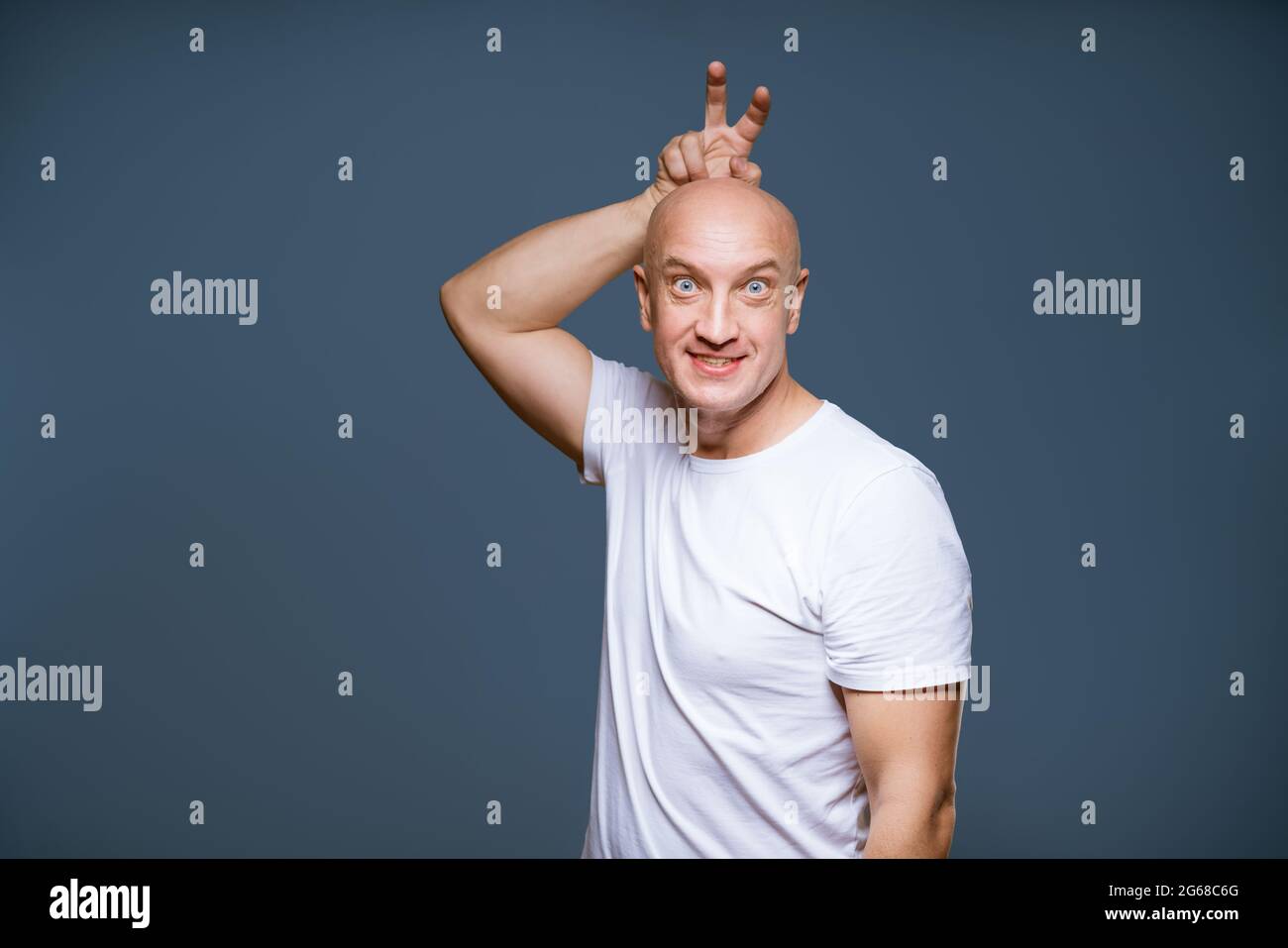 Funny bald male posing on a blue background with emotional facial ...