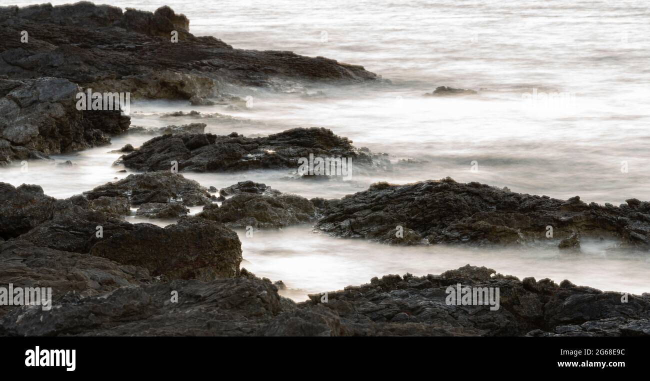 A photo of the blurry sea waves crashing on the rocky shore of the ...