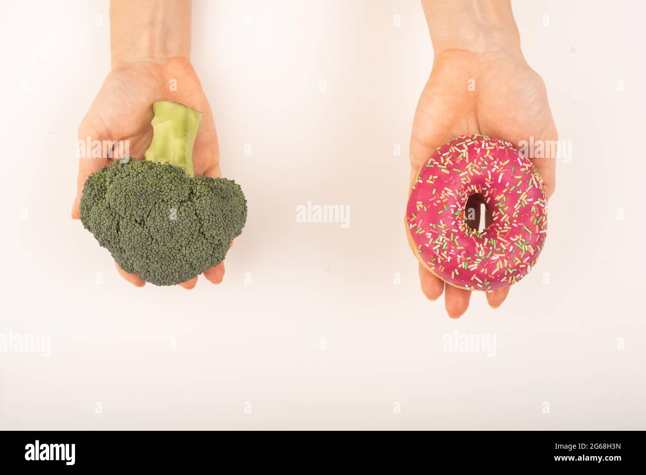 Comparison of eating habits. Woman holding broccoli and donut on a ...