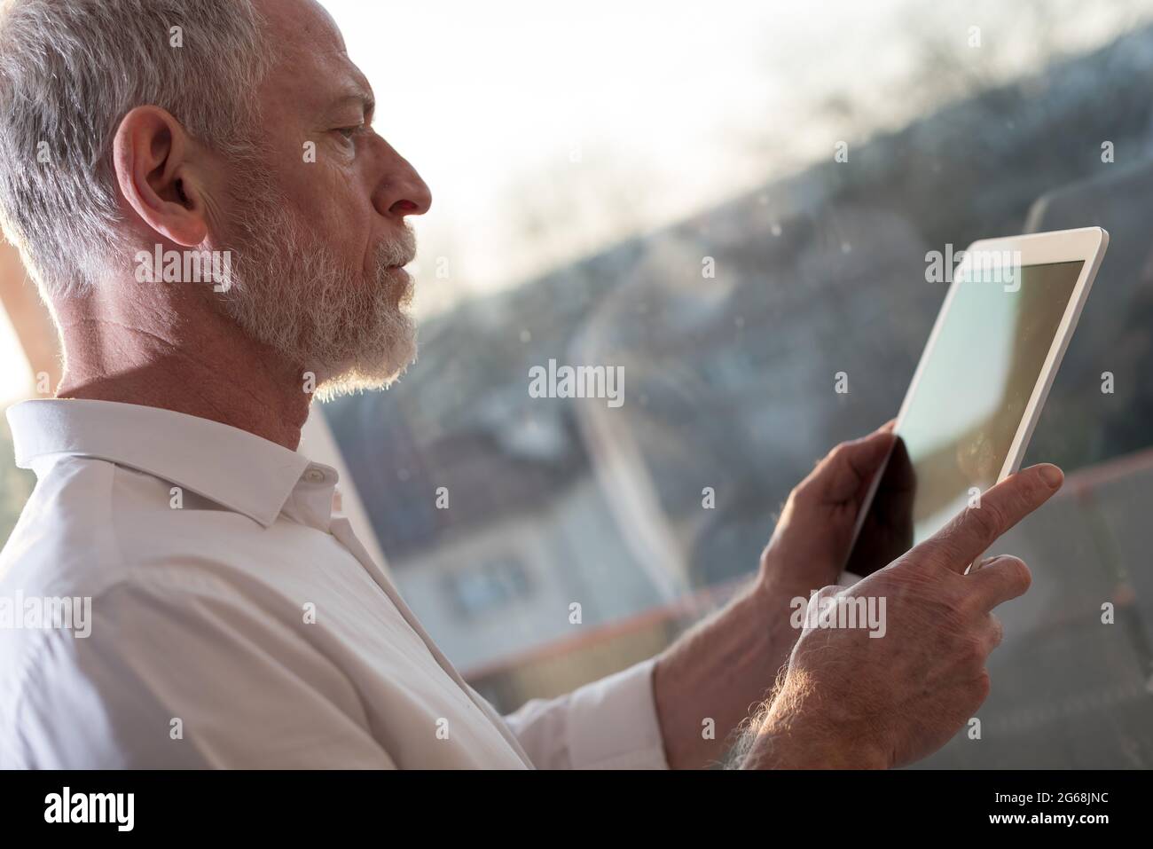 Senior businessman using a digital tablet in office, hard light Stock ...