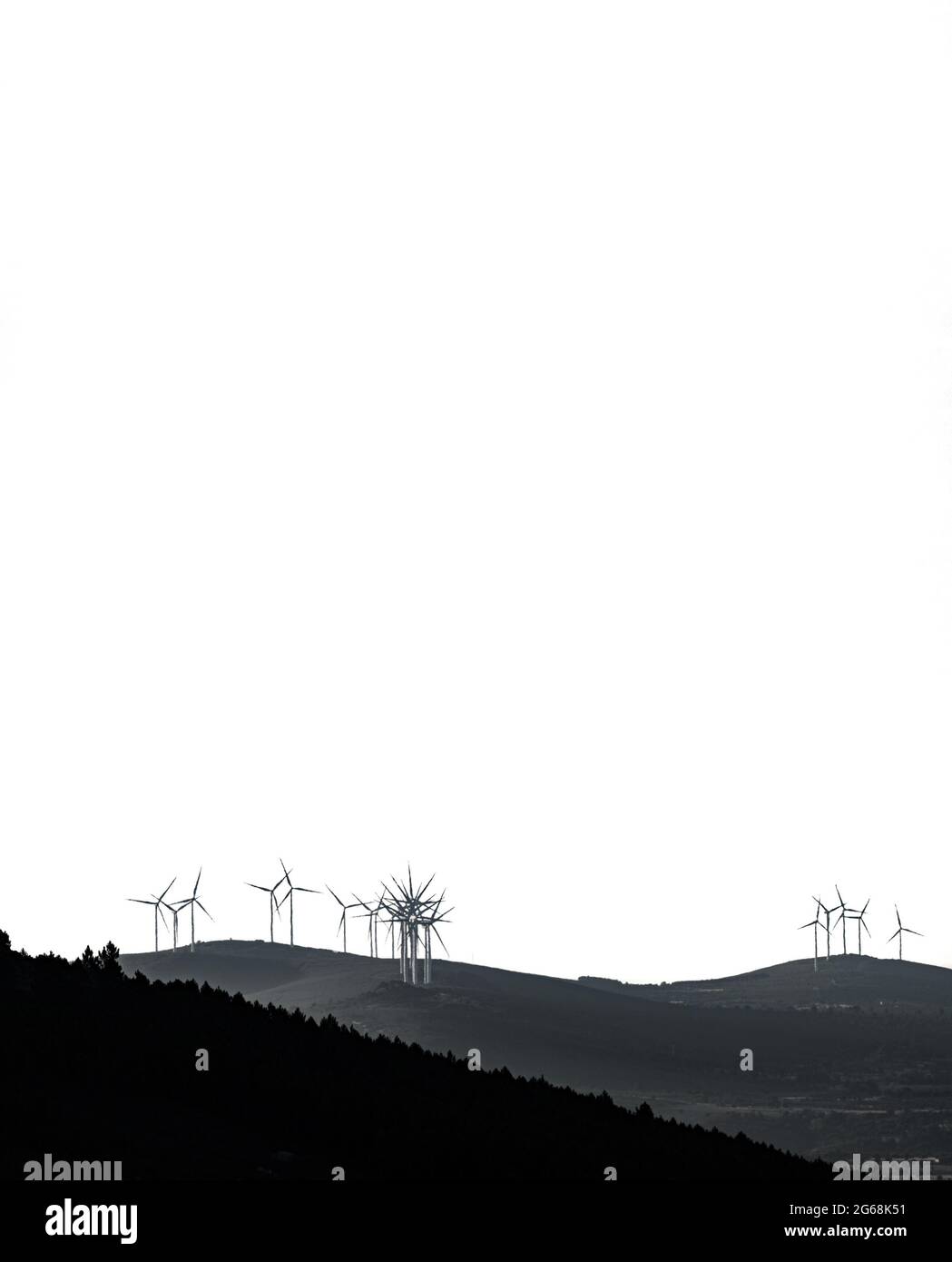 Windmill array over the mountain range against white sky Stock Photo ...