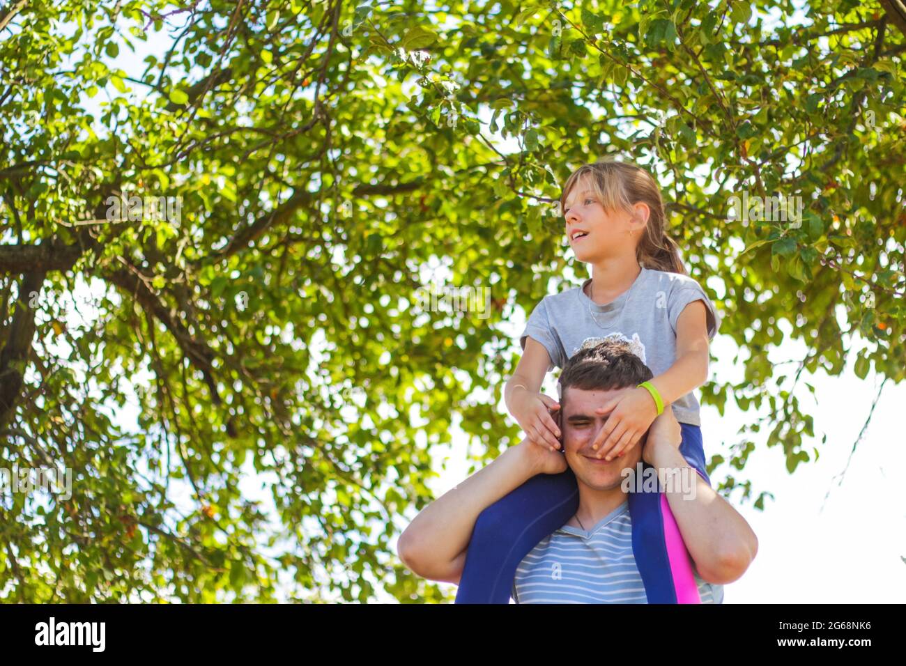 Defocused brother riding sister on back. Portrait of happy girl on man ...