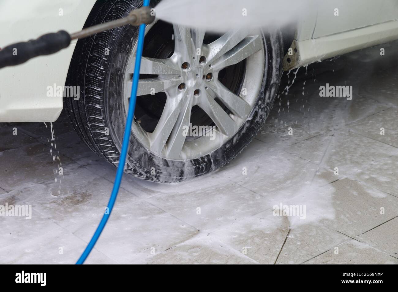 Washing a car wheel and tyre with a portable car wash, outdoor shot ...