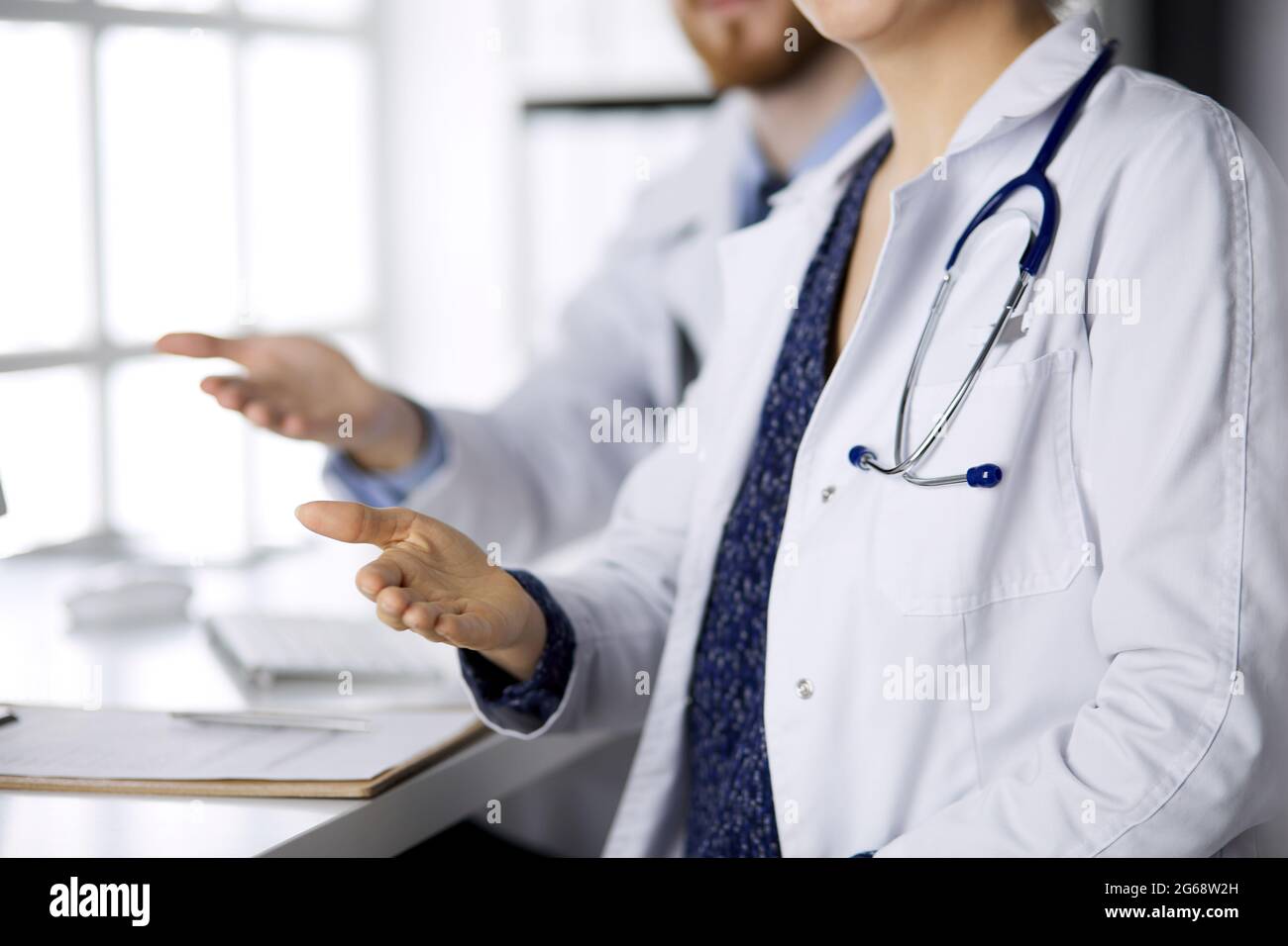 Two doctors sitting and offering helping hand for shaking hand or ...