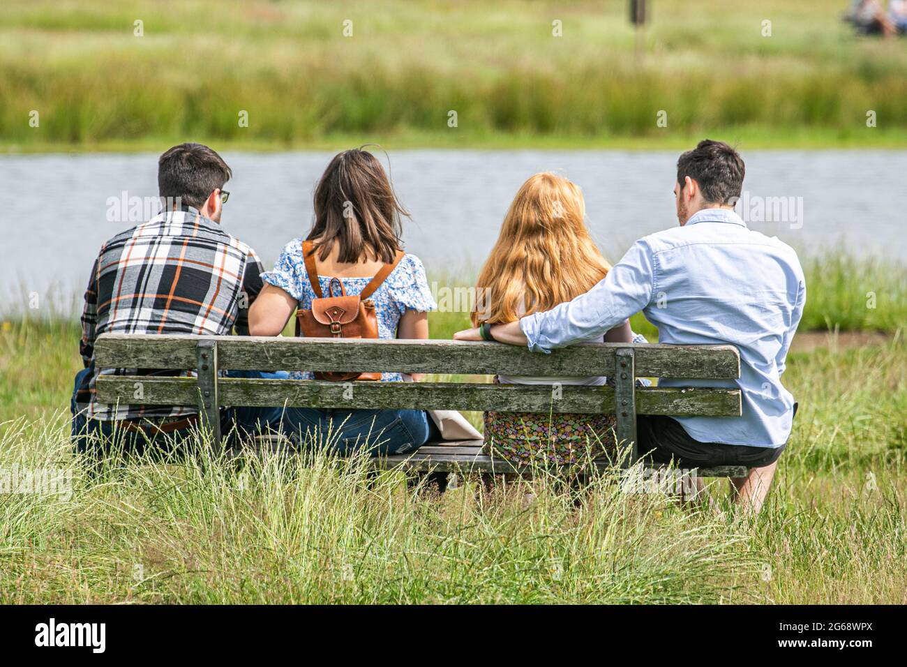 WIMBLEDON LONDON 4 July 2021. A group of friends sharing a bench ...