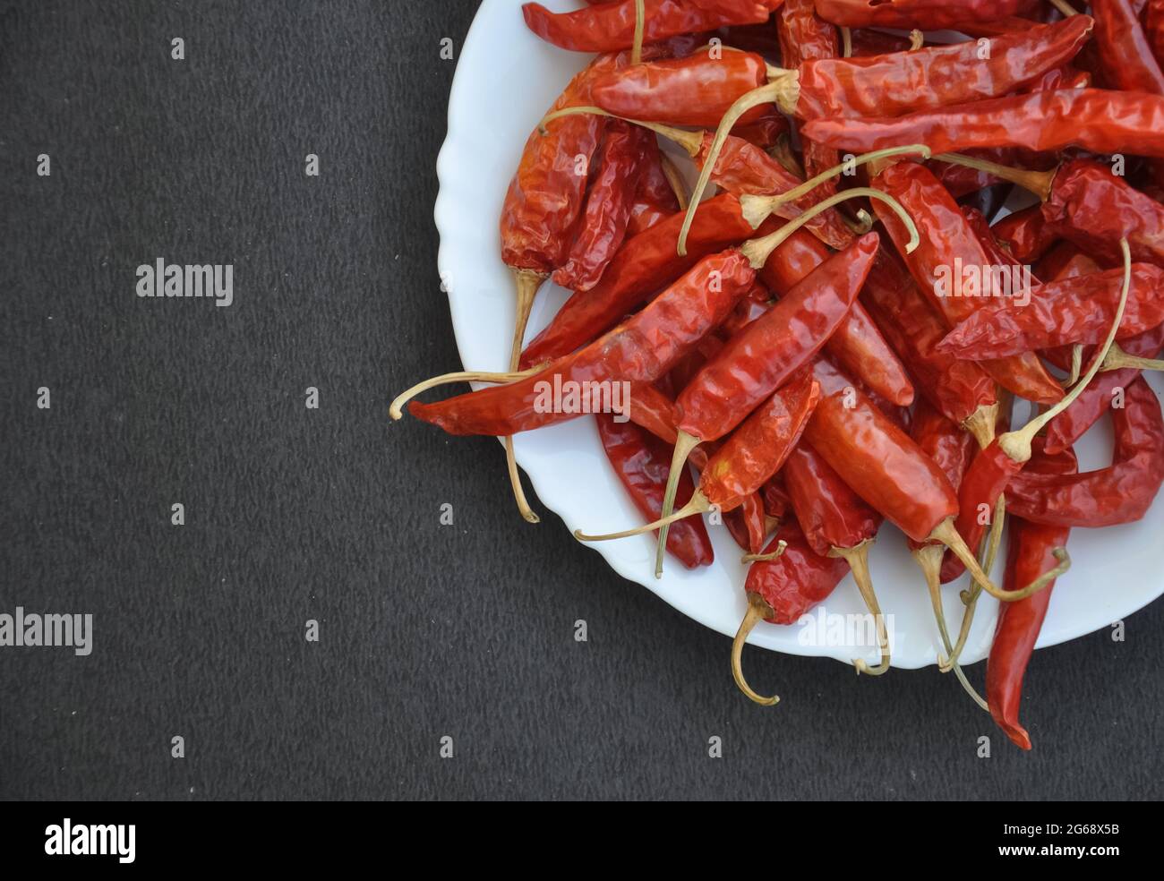 High angle of heap of red chilli peppers on the white plate isolated ...