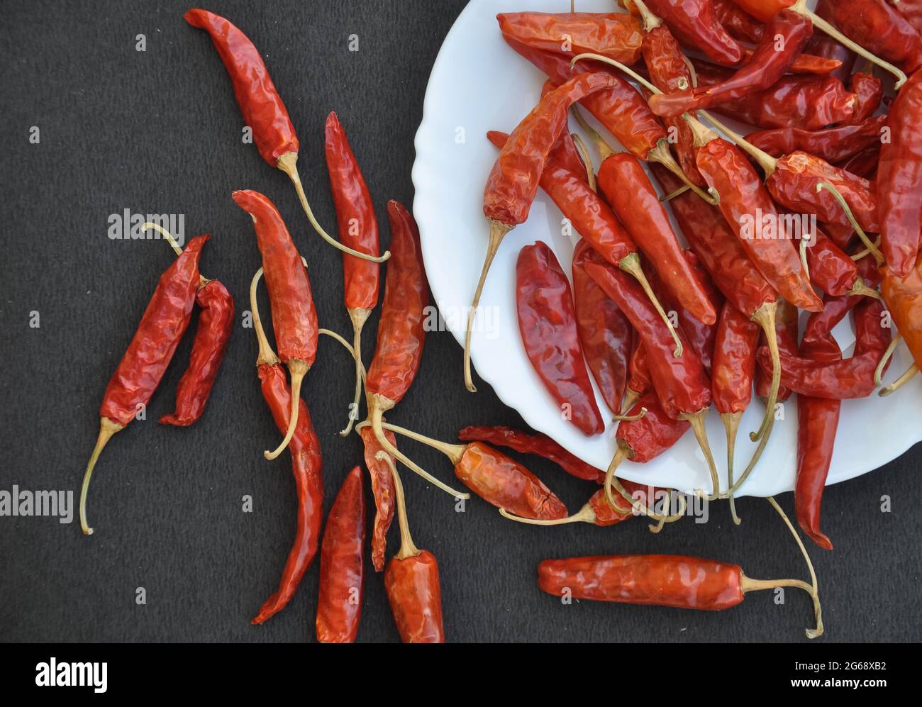 Overhead view of heap of red chilli peppers in white plate with spread ...