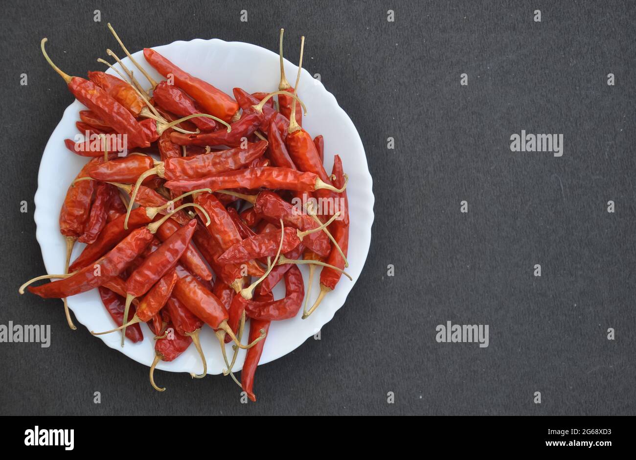 High angle of heap of red chilli peppers on the white plate isolated ...