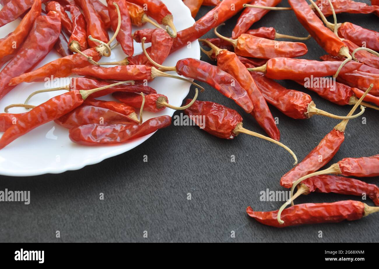 Close up of red chilli peppers in white plate with spread on rough ...