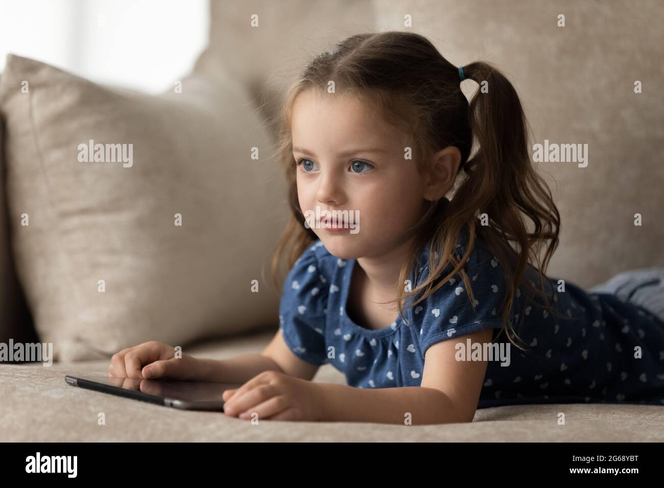 Close up little 7s girl relaxing on couch with tablet Stock Photo - Alamy