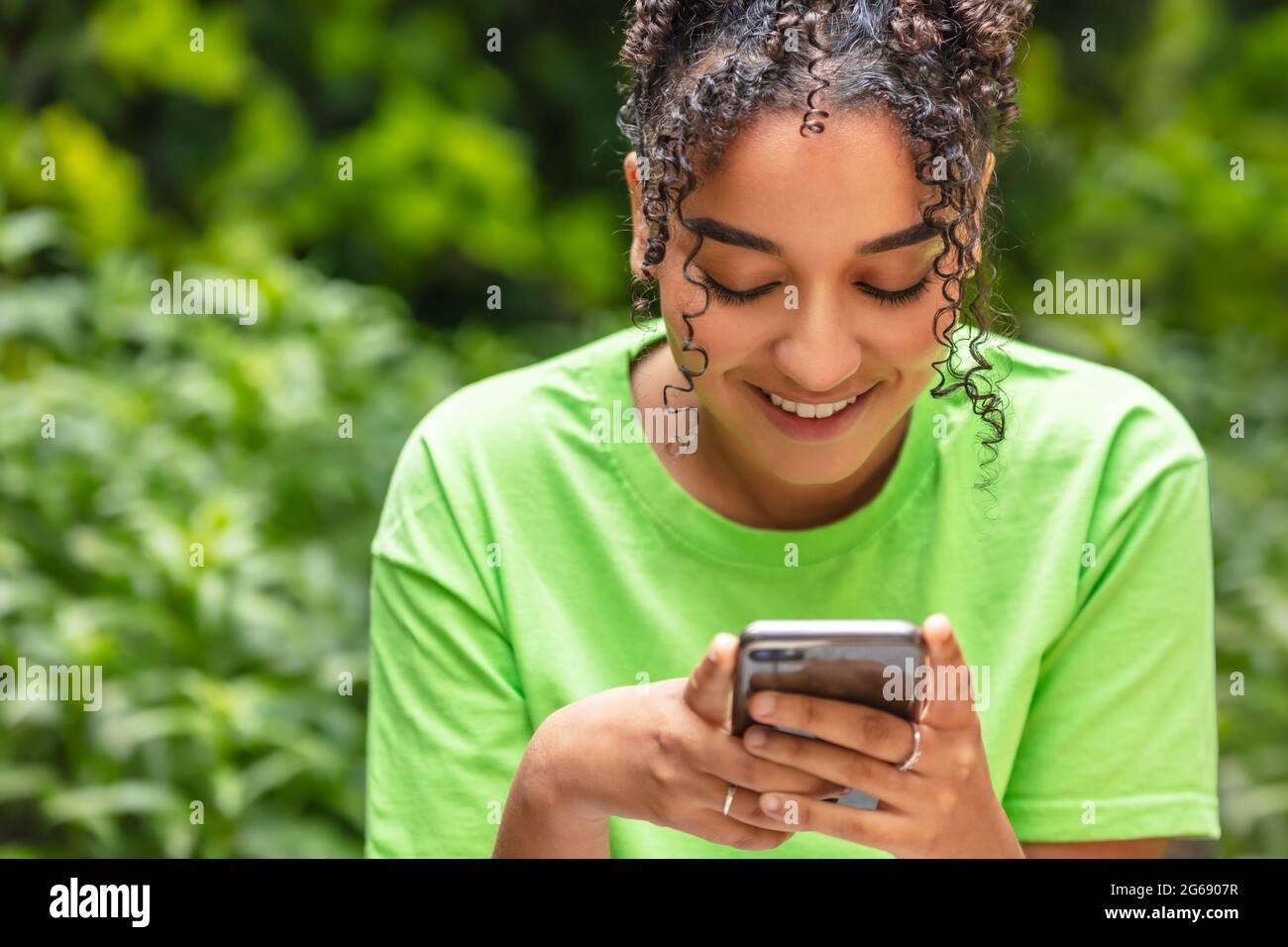 Outdoor portrait of beautiful happy mixed race African American girl teenager female young woman ...