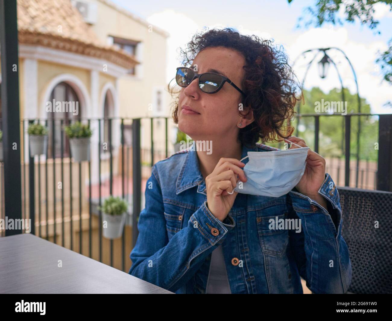 Woman removing face mask sitting at restaurant table Stock Photo - Alamy