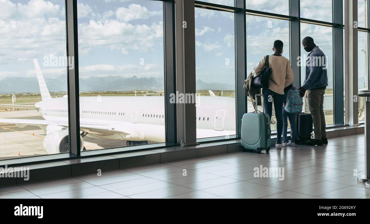Wide angle view of family of three standing at airport terminal with ...