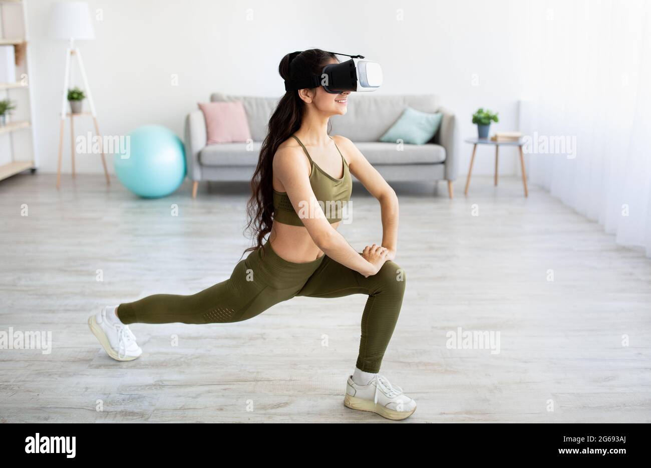 Athletic Indian lady wearing VR headset, doing virtual workout in ...