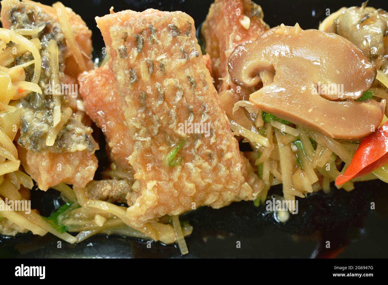 deep fried slice striped snake head fish with ginger and celery on dish ...