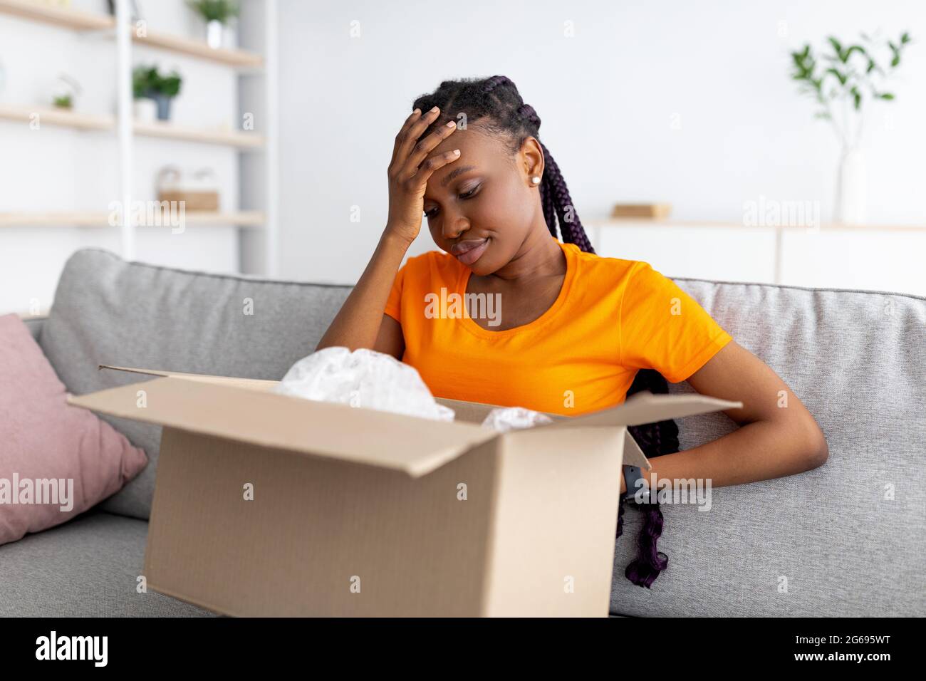 Disappointed black woman unboxing her delivery, looking inside wrong ...