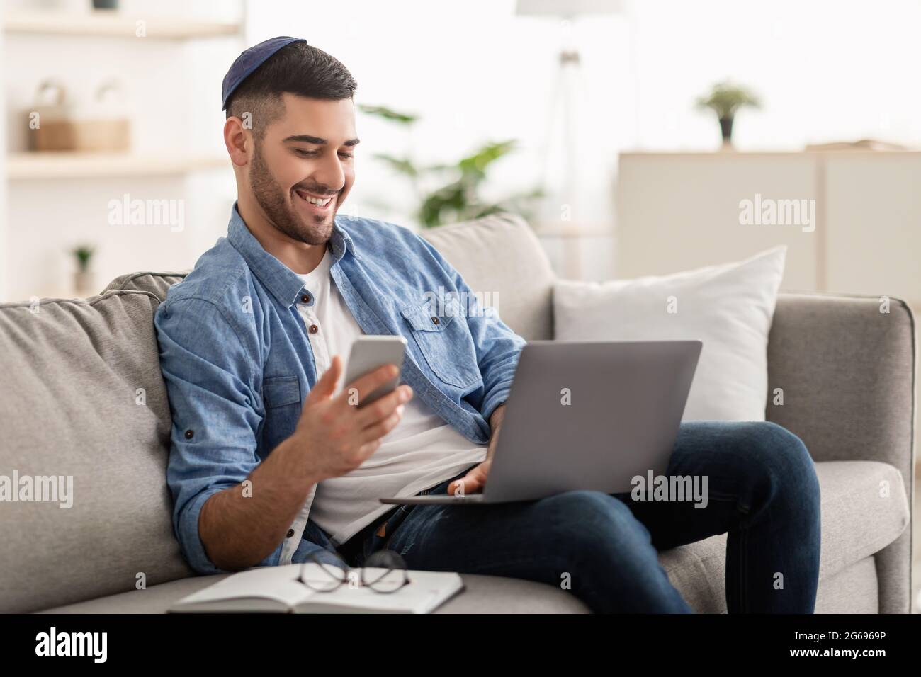 Happy jewish man using mobile phone and laptop Stock Photo - Alamy