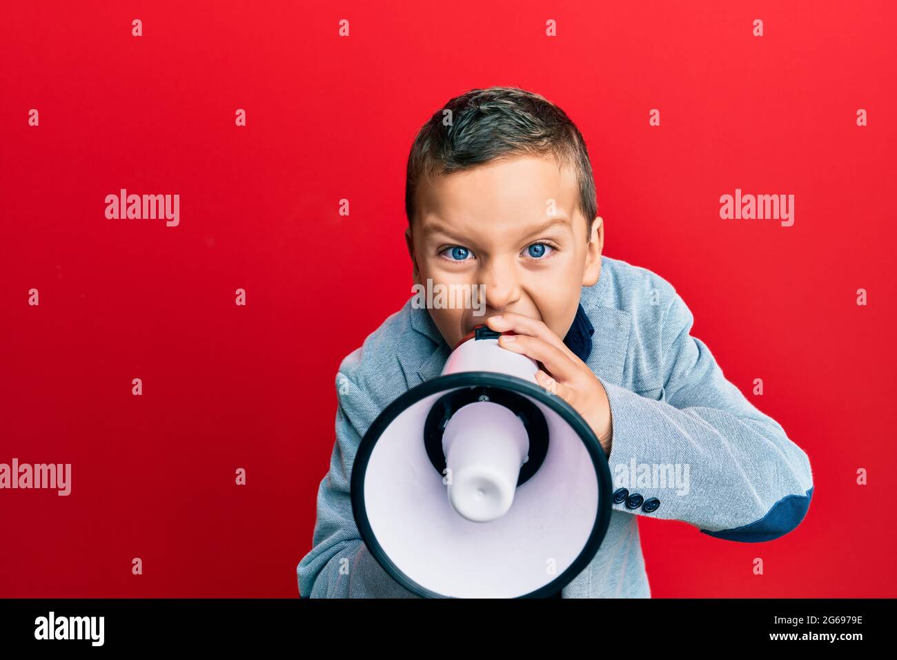 Adorable caucasian boy screaming using megaphone over isolated red ...