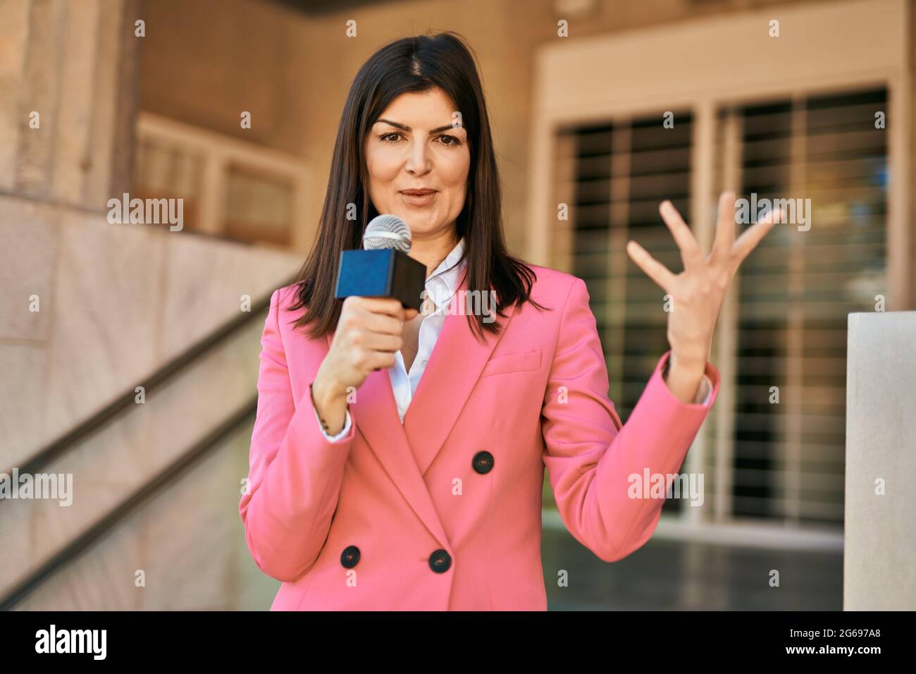 Middle age reporter woman holding microphone doing television speech ...