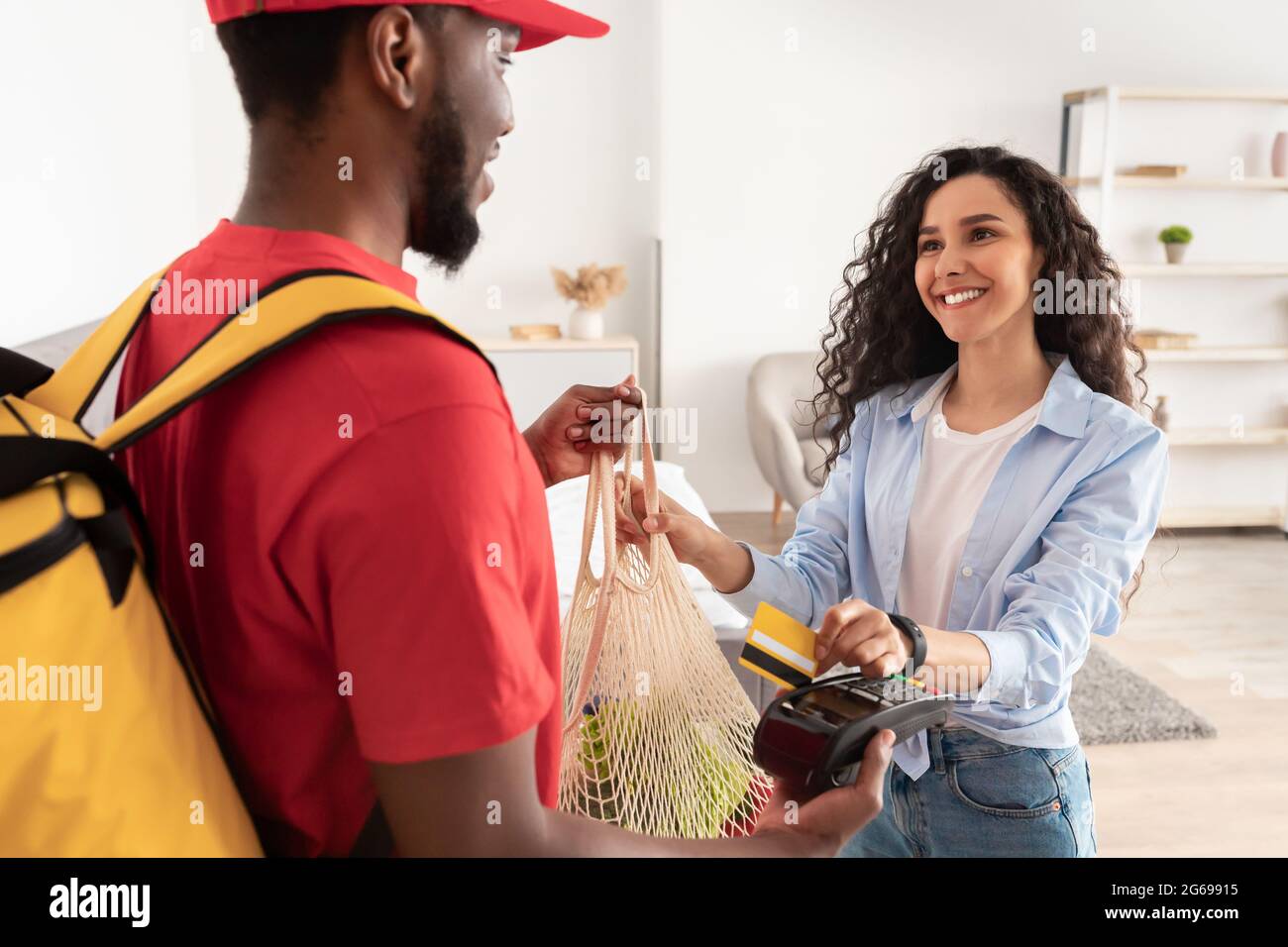 Black man holding POS machine, client paying with card Stock Photo - Alamy