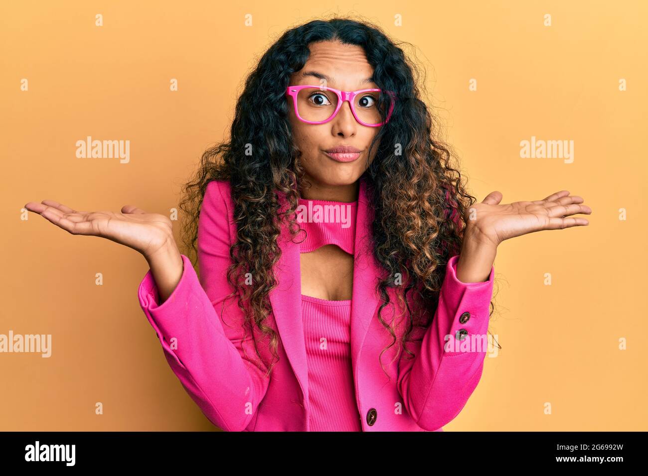 Young latin woman wearing business style and glasses clueless and ...