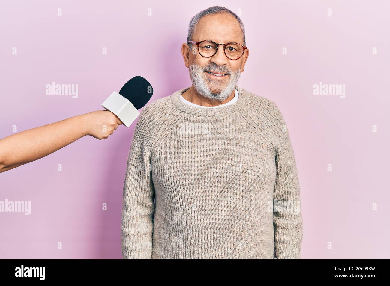 Handsome senior man with beard being interviewed by reporter holding ...