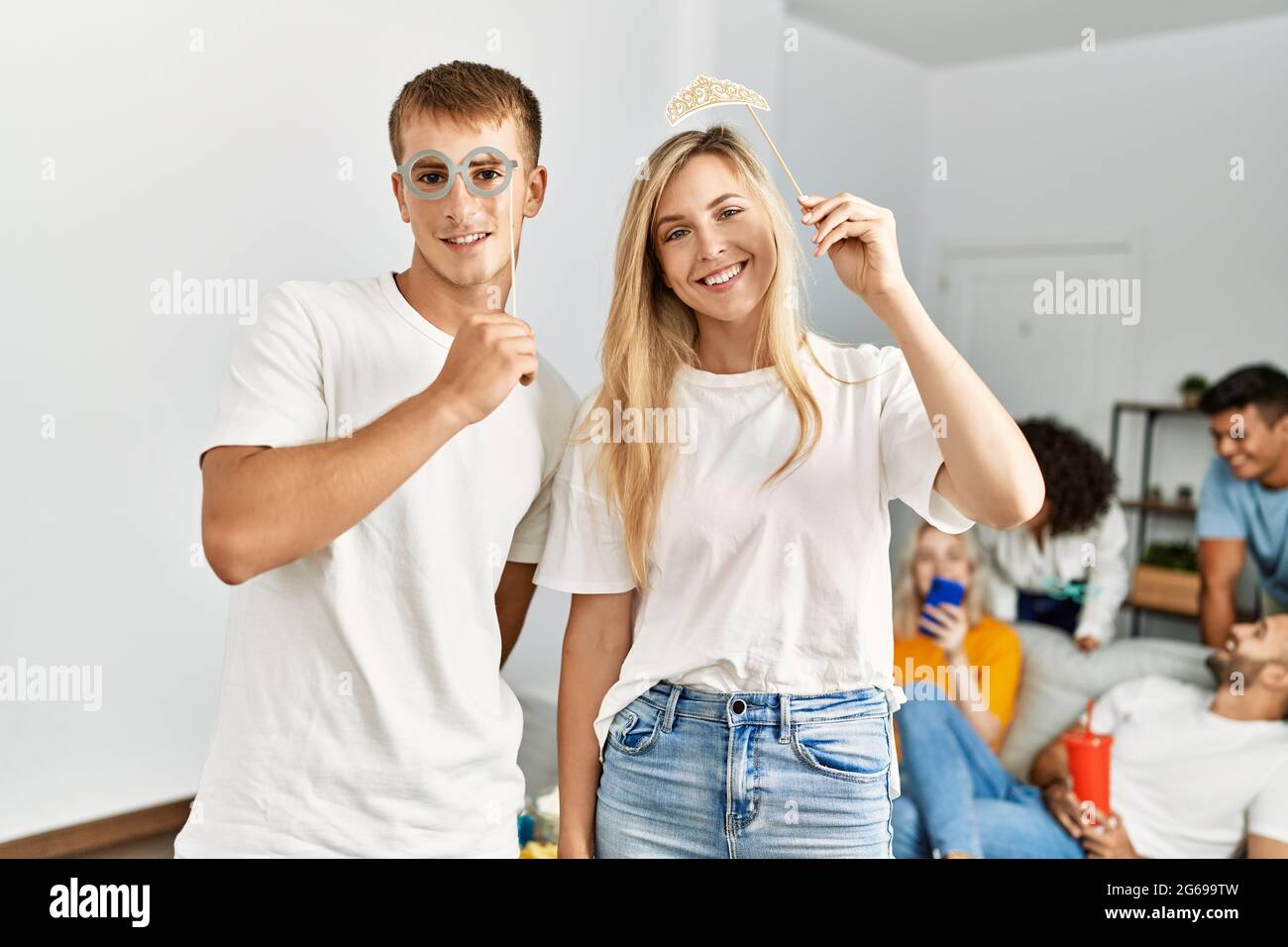 Two young friends having party using funny costume accessories at home ...